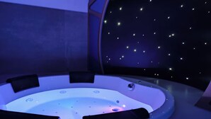 Uma banheira de hidromassagem circular com um painel de parede com tema de estrelas.