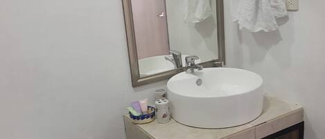 Casa de banho com uma pia branca, um espelho, um porta-toalhas e uma sanita.