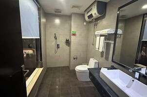 Uma casa de banho moderna com chuveiro, sanita e uma grande pia.