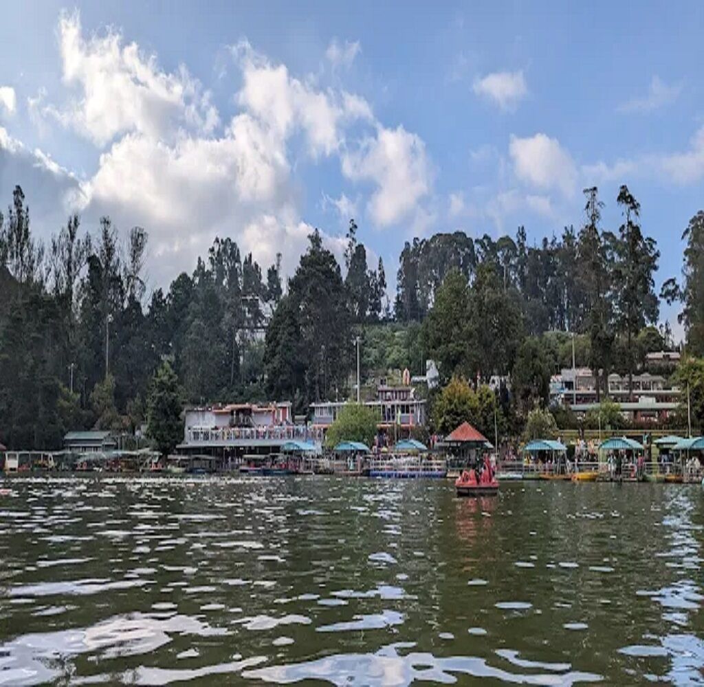 Vista para um lago com barcos, um cais e edifícios ao fundo.