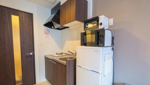 Uma cozinha compacta com micro-ondas integrado, geladeira branca e fogão a gás.