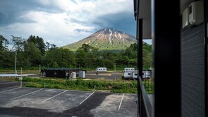Um parque de estacionamento com veículos recreativos, um pequeno edifício e uma montanha ao fundo.