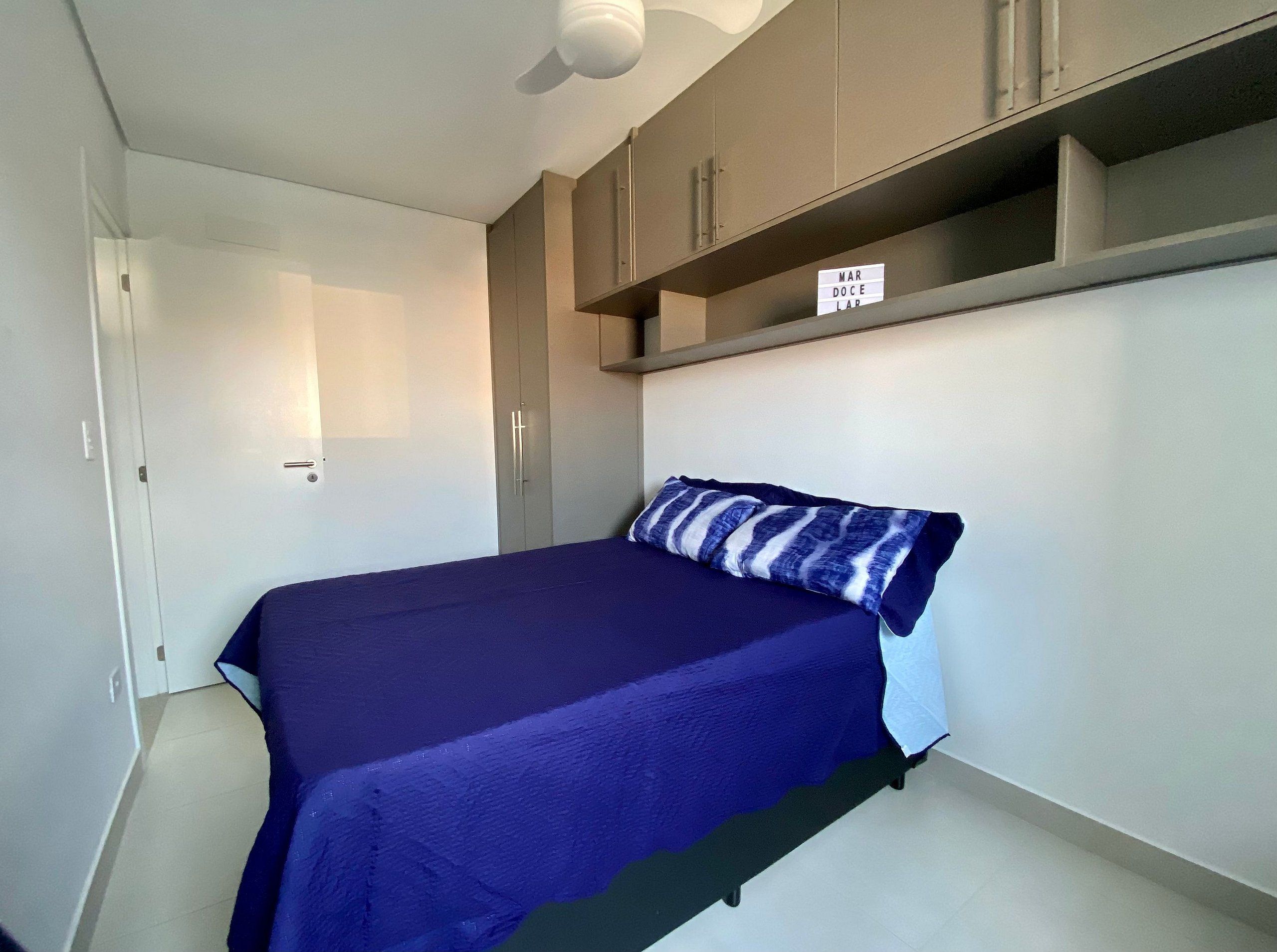 Quarto com cama, guarda-roupa e prateleira com um aviso.