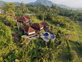 Um resort tropical com vários edifícios, piscina e vegetação exuberante.
