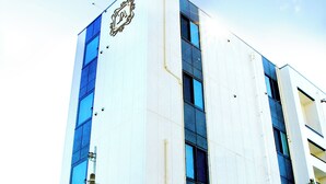 Um edifício moderno com um logotipo em destaque no topo, várias janelas e um letreiro do jornal Times visível à esquerda.