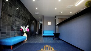 Um corredor com um banco azul, um vaso com flores e um tapete com um logotipo.