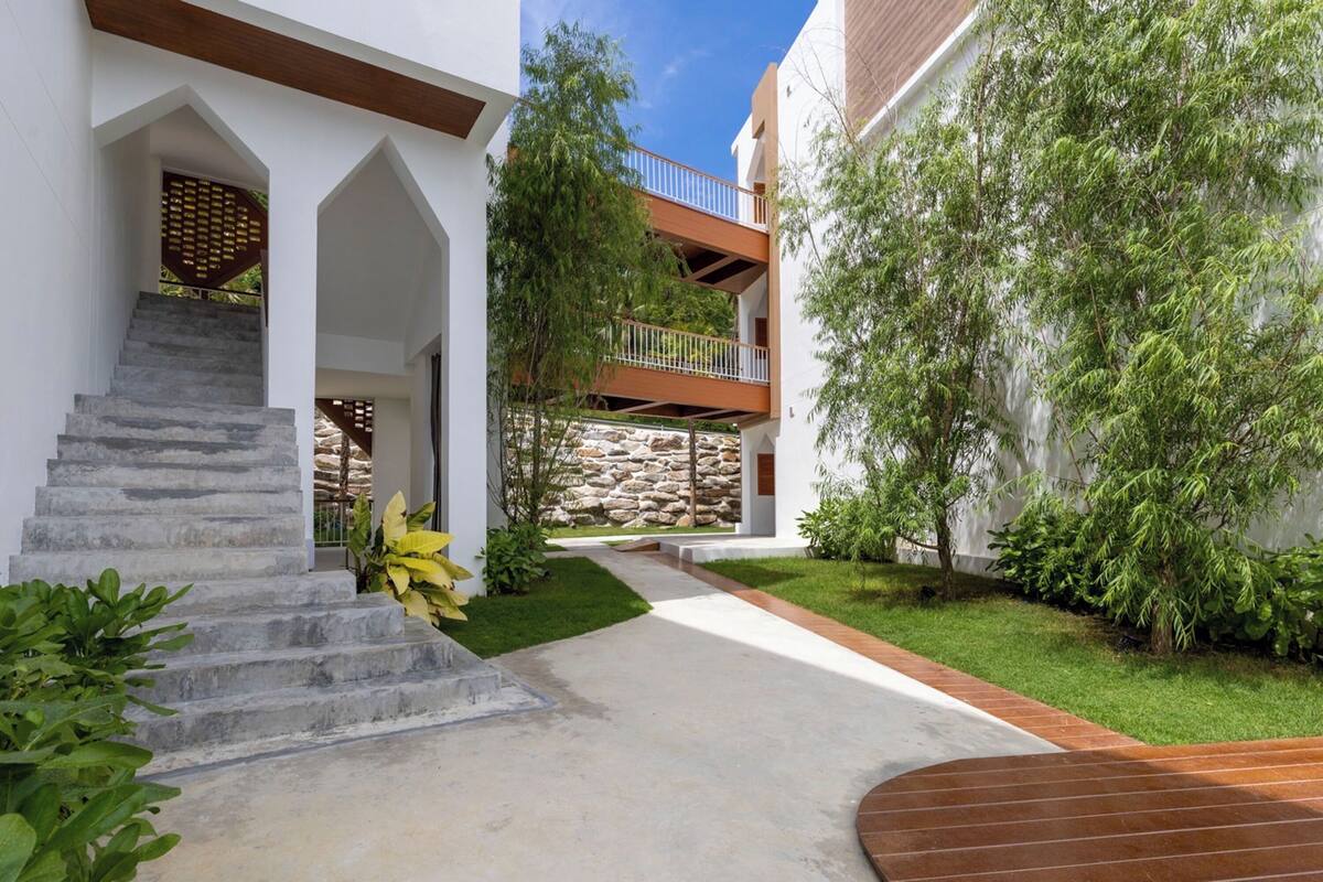 Um edifício moderno com escadaria de pedra, deck de madeira e jardim bem cuidado.