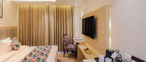 Quarto de hotel com cama, escrivaninha, cadeira, televisão e bandeja de café da manhã.