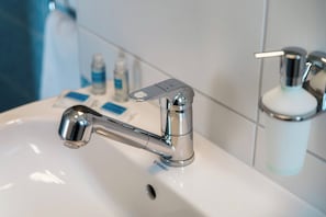 Uma pia de banheiro com uma torneira moderna e um dispensador de sabonete.