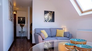 Uma sala de estar moderna com um sofá cinzento, uma mesa de centro de vidro e tigelas decorativas.
