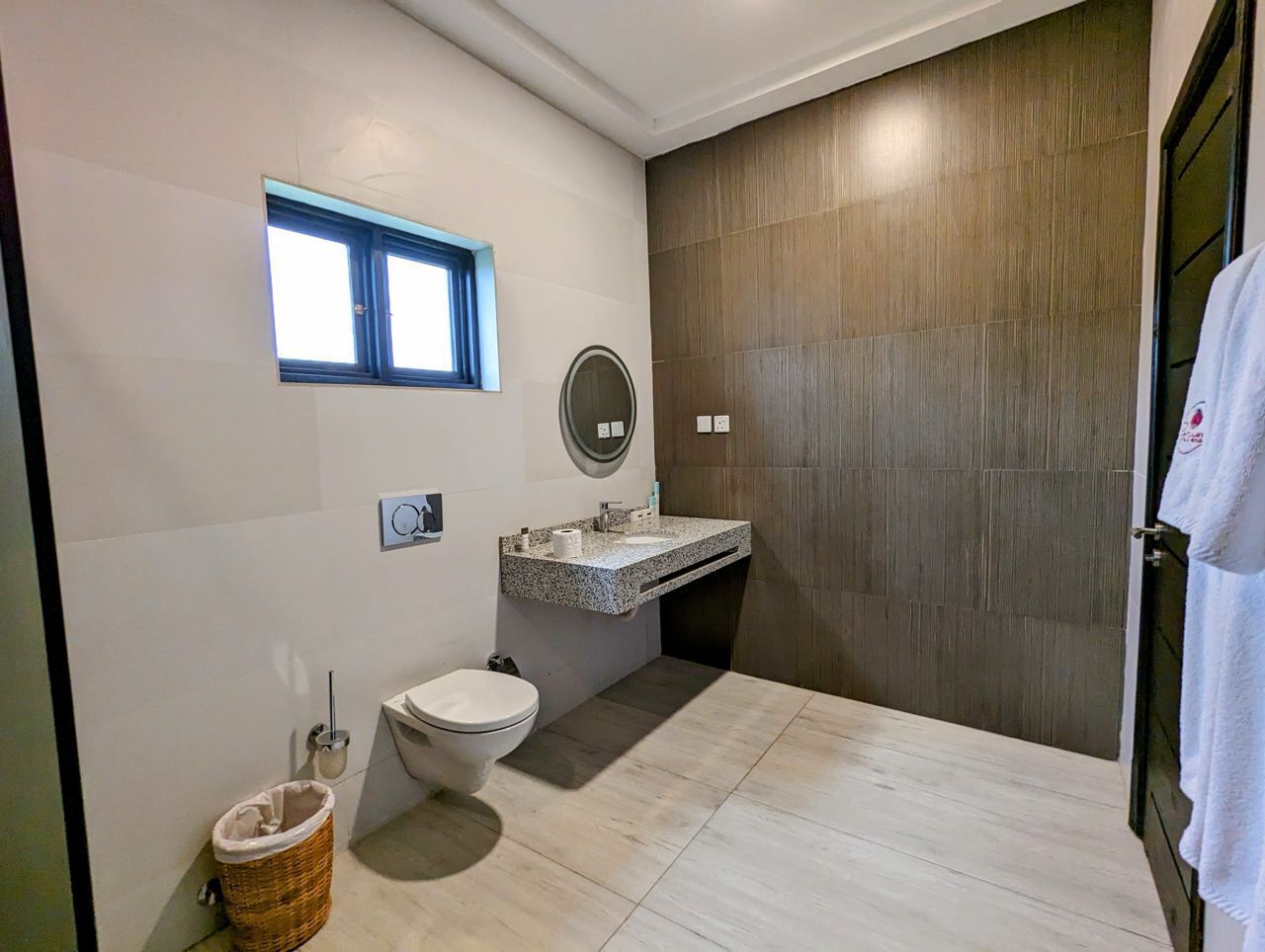 Casa de banho moderna com sanita, lavatório e uma pequena janela.