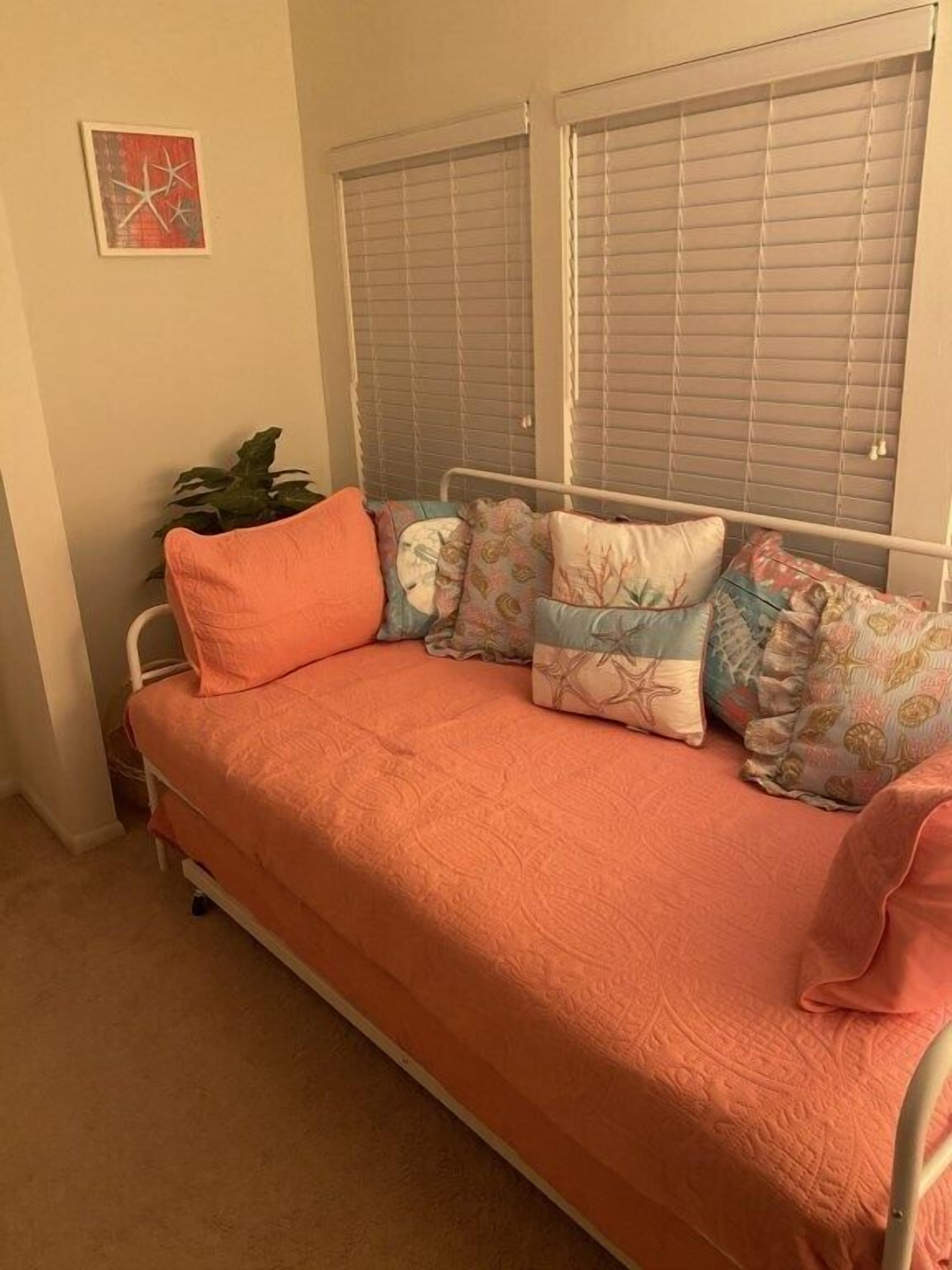 Um quarto pequeno e acolhedor com uma cama de solteiro, uma planta em vaso e um quadro na parede.