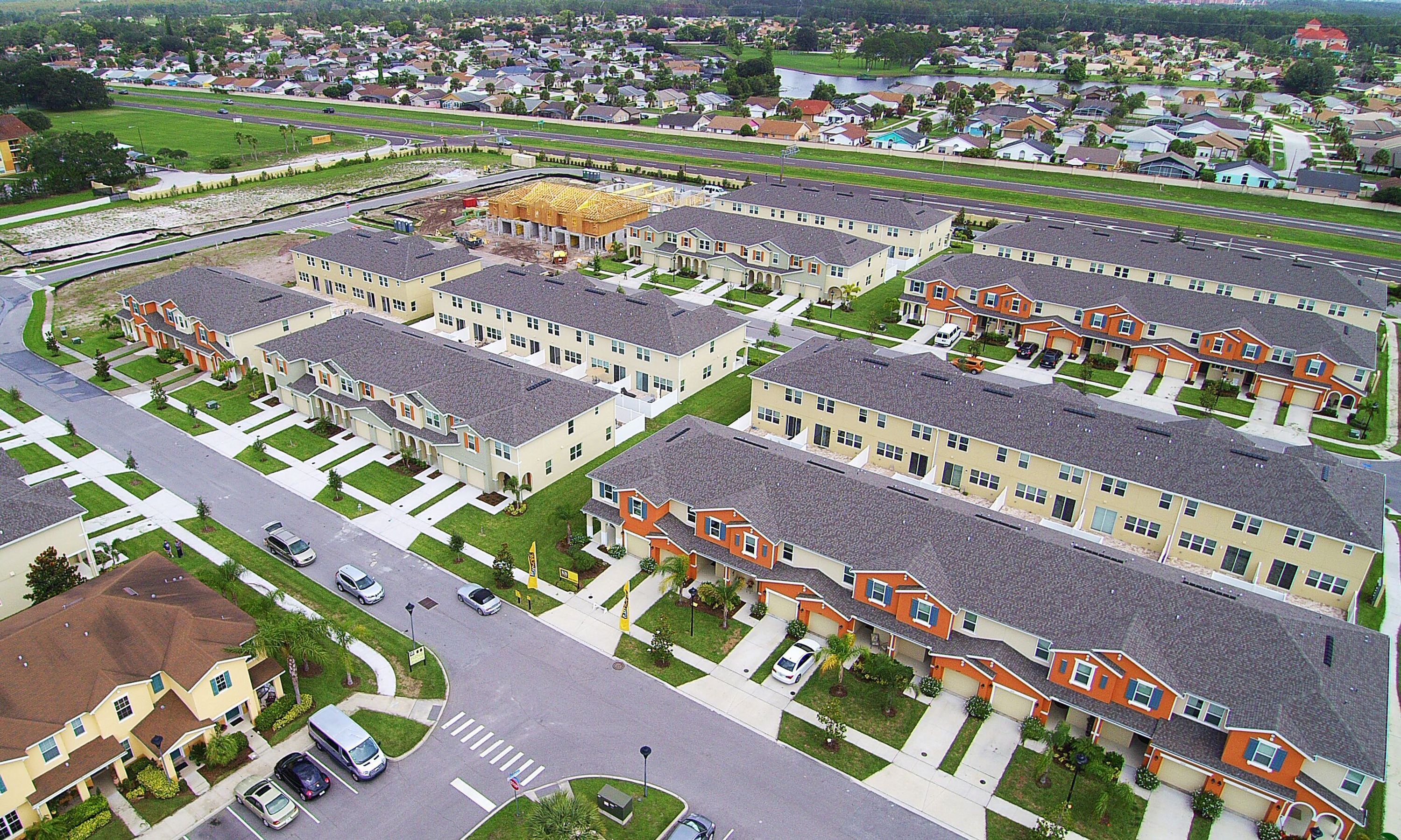 Zona residencial com várias casas de dois andares, uma avenida principal e um amplo espaço aberto com um edifício em construção.
