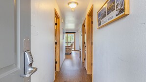 Um corredor com fechadura moderna, portas de madeira, uma fotografia emoldurada de uma cordilheira e piso coberto de carpete.