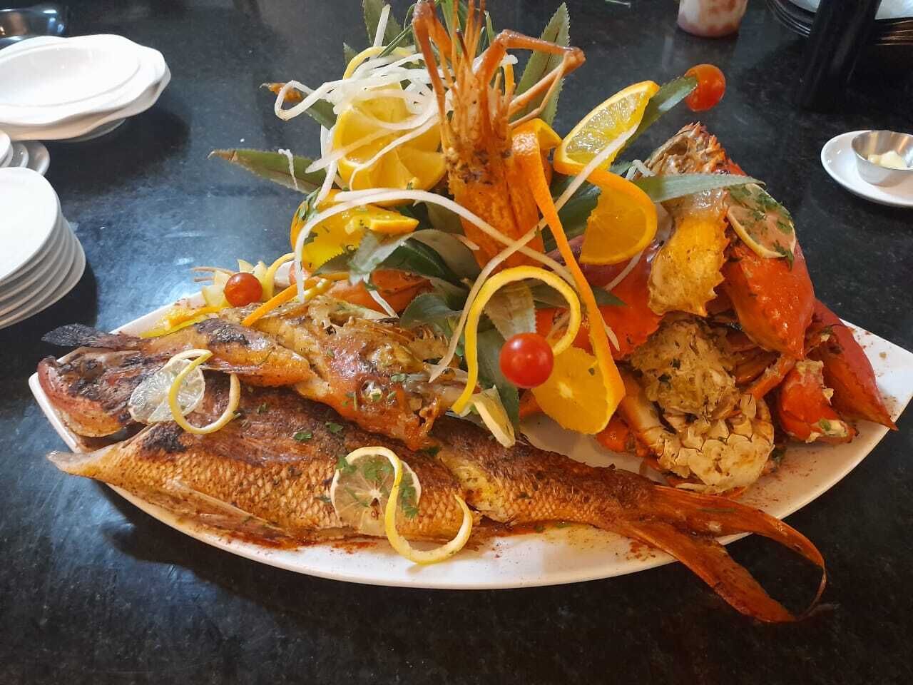Prato de frutos do mar com peixe inteiro, caranguejo e legumes.