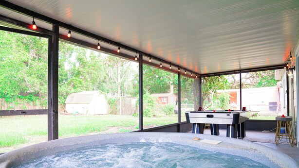 Área de hidromassagem com mesa de bilhar e vista para o quintal.