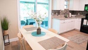 Uma cozinha moderna com armários brancos, bancada de granito e área de jantar com mesa e cadeiras.