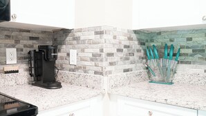 Uma cozinha com bancada de granito, cafeteira e porta-facas.