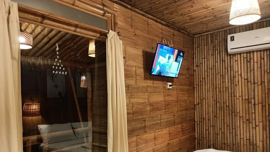 Quarto com parede de madeira, televisão fixada na parede e cama com cabeceira branca.