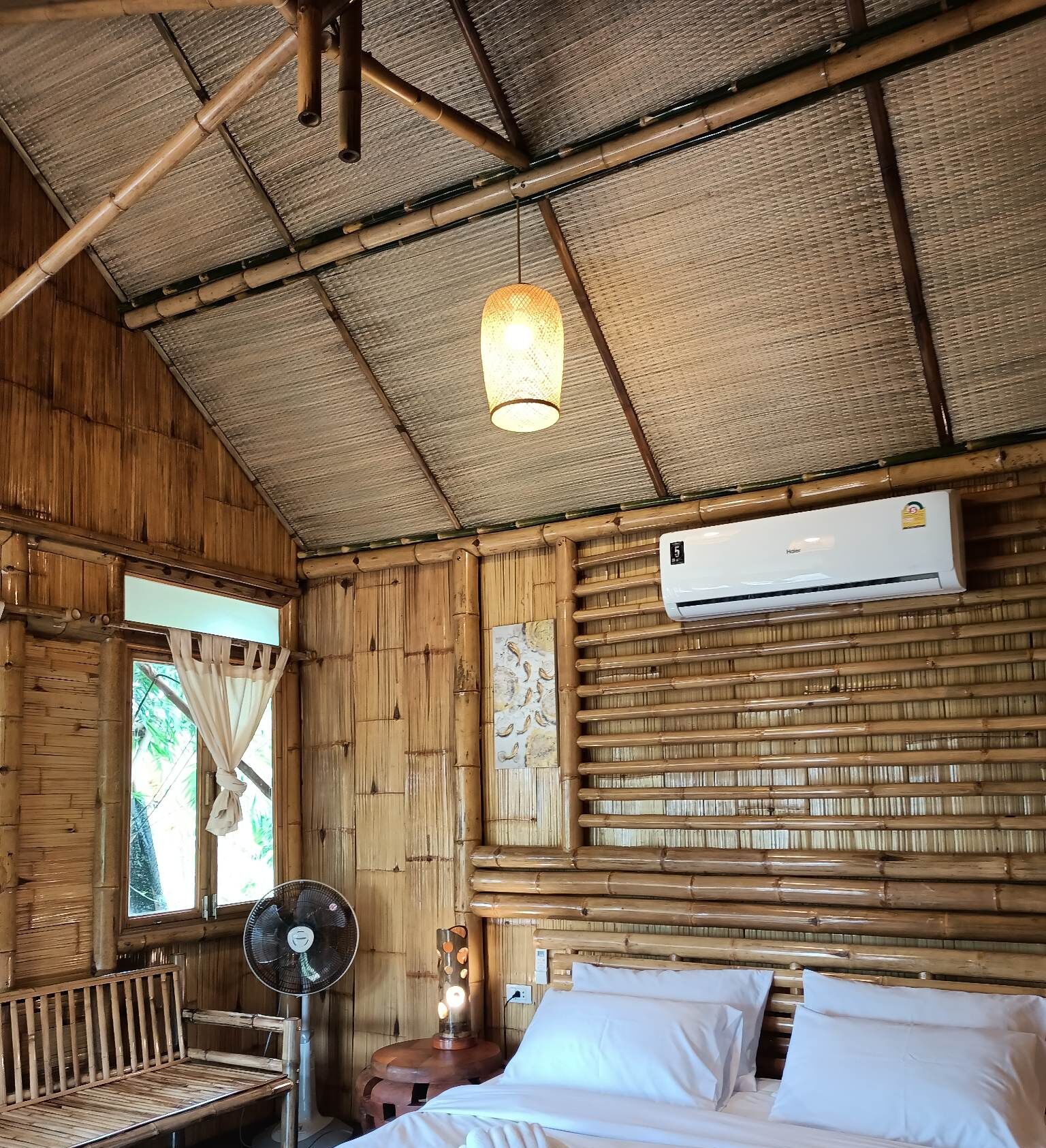 Quarto com cama, ventoinha, mesa e ar condicionado.