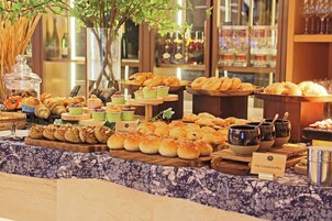 Buffet com diversos pães e doces.