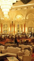 Um amplo saguão de hotel com lustres ornamentados, grandes janelas e áreas de estar confortáveis.