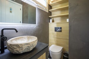 Uma casa de banho moderna com lavatório de pedra, espelho e sanita.