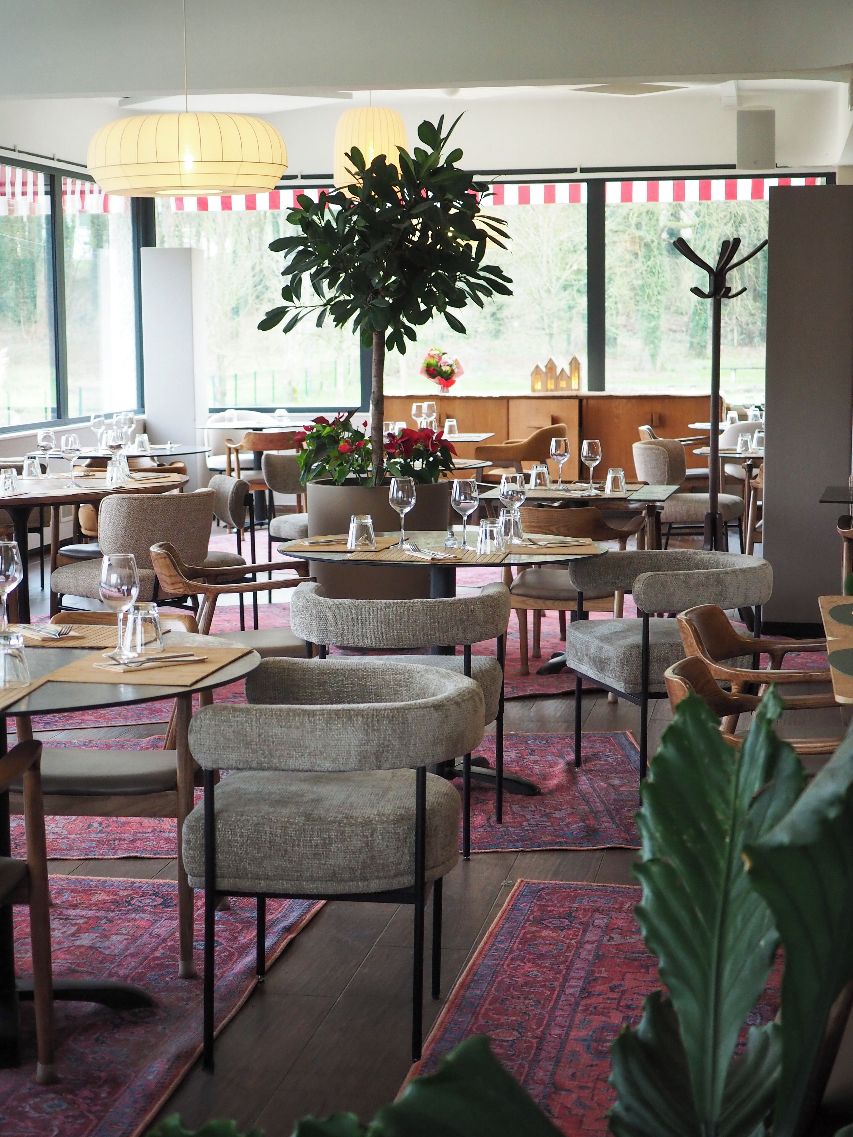 Um restaurante com mesas redondas, cadeiras e plantas em vasos.