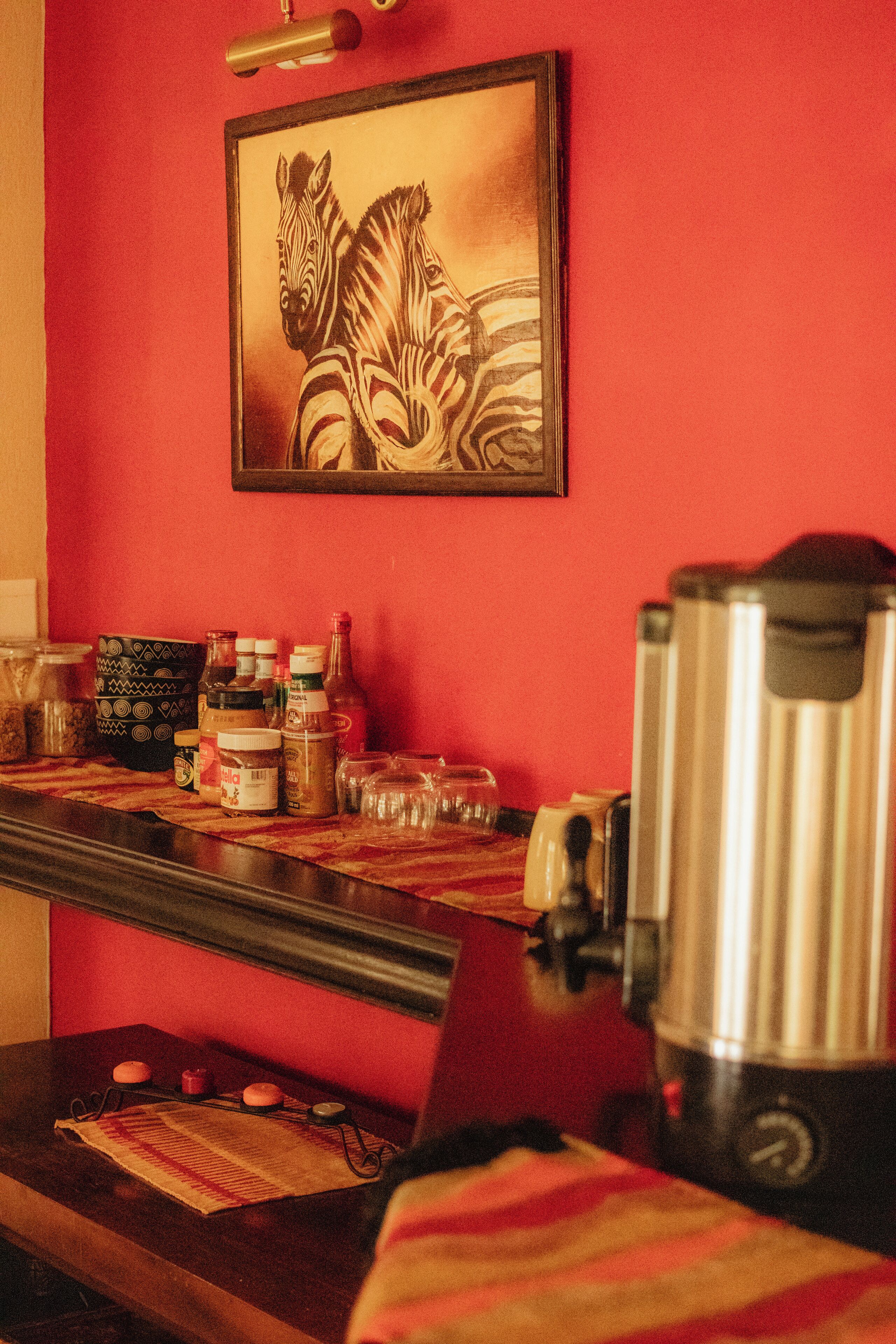 Uma bancada de cozinha com uma cafeteira, potes e um quadro de uma zebra na parede.
