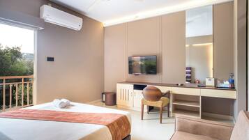 Quarto de hotel com cama, escrivaninha, cadeira, televisão e varanda.