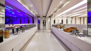 Uma área de buffet moderna e bem iluminada, com diversos alimentos e utensílios.