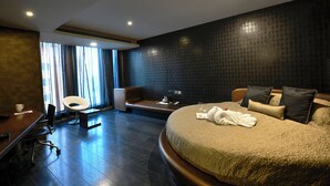 Quarto de hotel moderno com uma cama grande, uma escrivaninha e um espaço de estar.