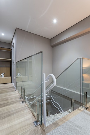 Um interior moderno com escada de vidro, piso de madeira e design minimalista.
