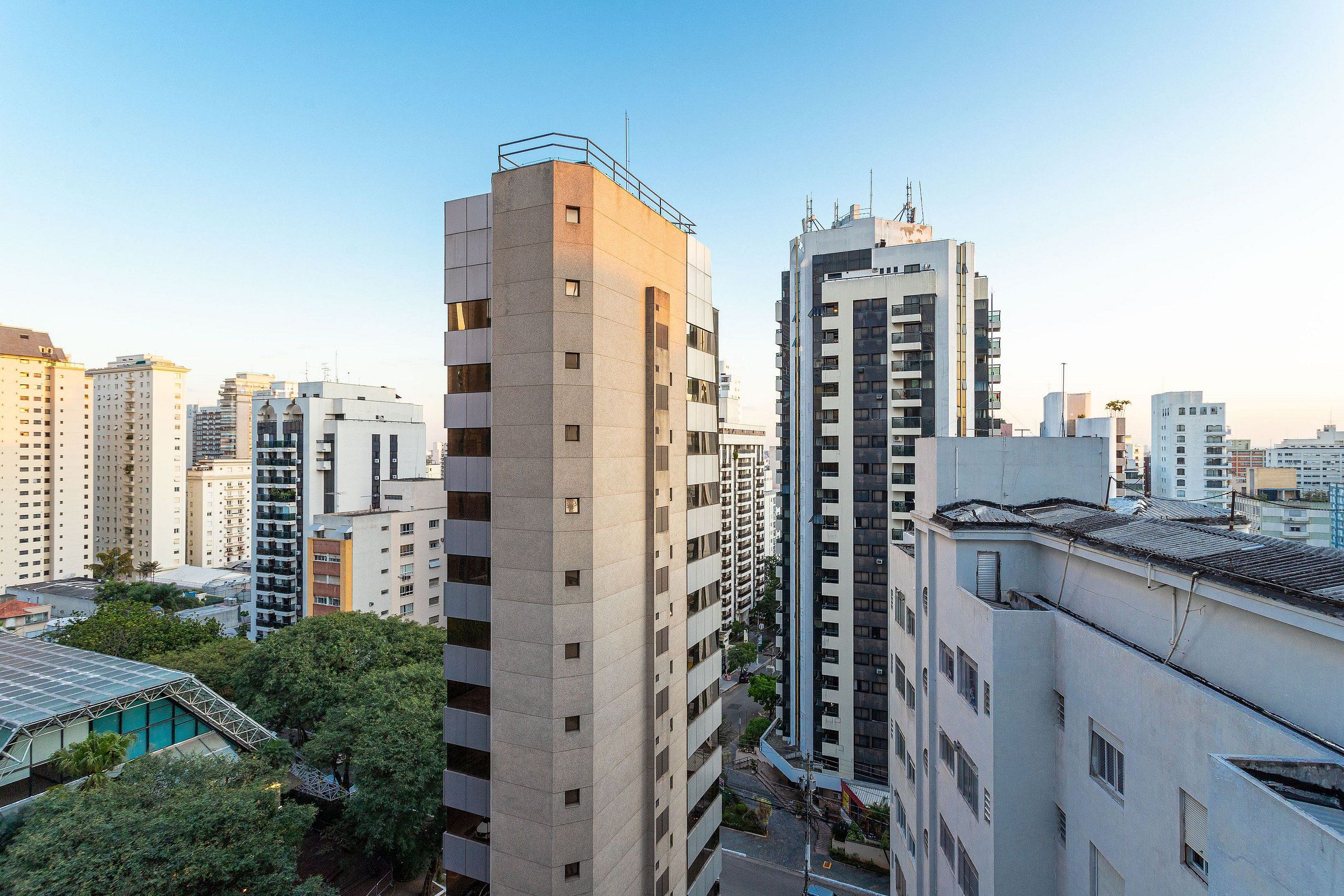 Um edifício alto com design arquitetônico moderno, apresentando uma estrutura de canto imponente e uma série de varandas.