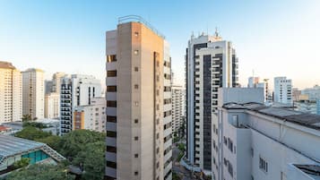 Um edifício alto com design arquitetônico moderno, apresentando uma estrutura de canto imponente e uma série de varandas.