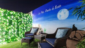 Uma área externa com assentos de vime e um mural representando o céu noturno.