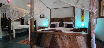 Cama com estrutura de madeira e dossel, mesa de cabeceira com abajur e criado-mudo com luminária.