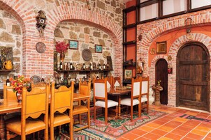 Uma sala de jantar com paredes de tijolo, móveis de madeira e piso de azulejos.