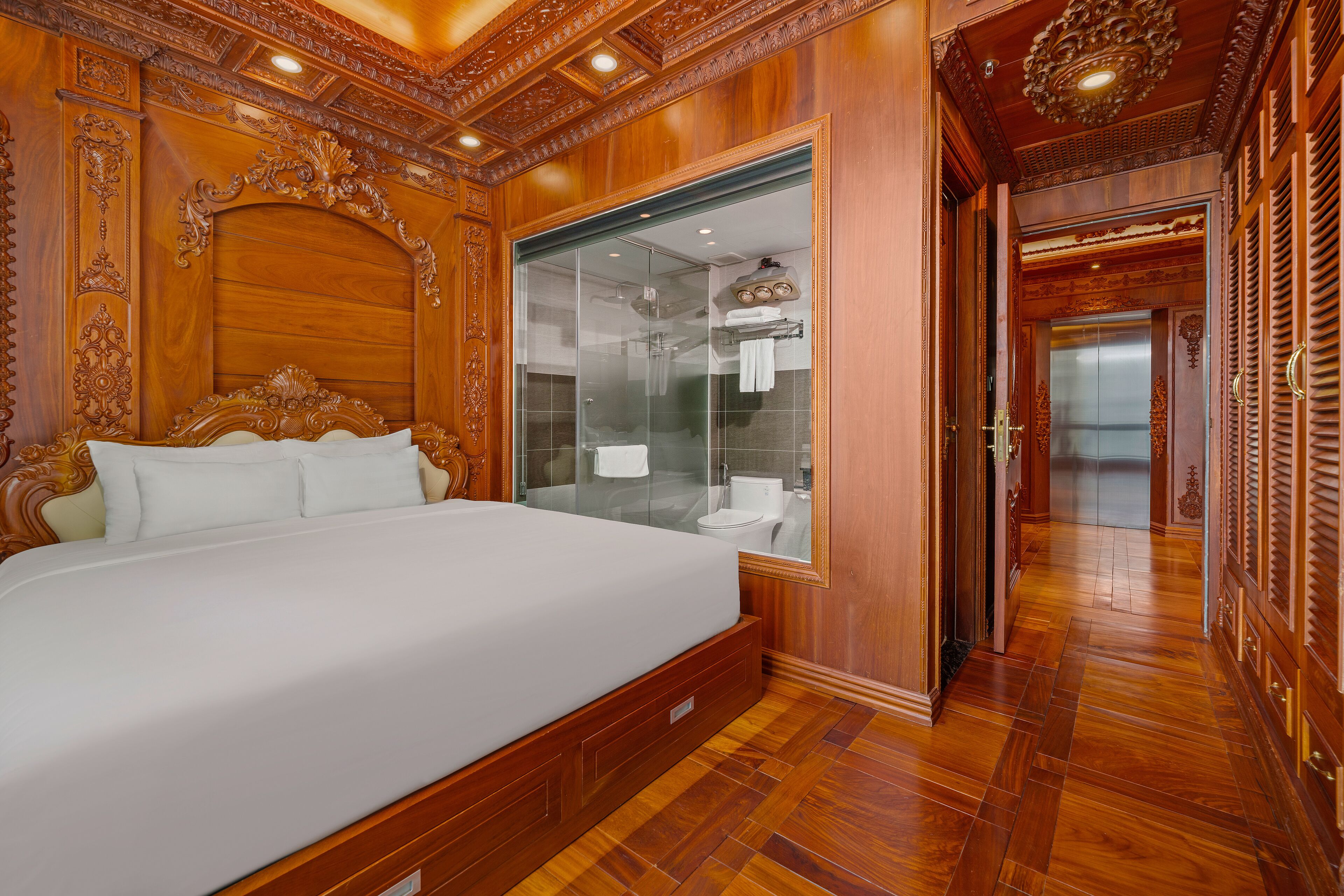 Um quarto luxuoso com uma elaborada cabeceira de madeira, uma cama grande e um espaço de chuveiro com divisória de vidro.