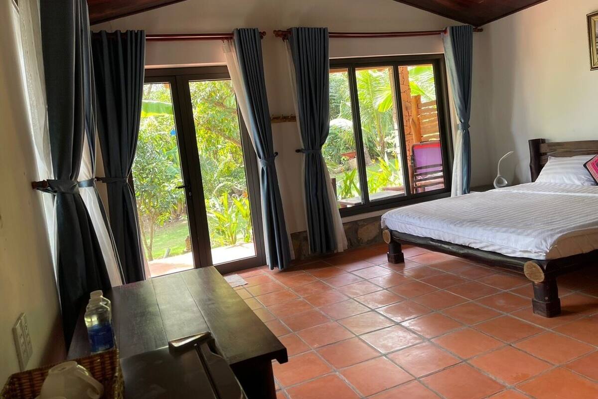Um quarto com uma cama, uma mesa e cortinas.