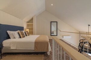 Quarto com uma cama, um corrimão de madeira e vista para uma varanda.