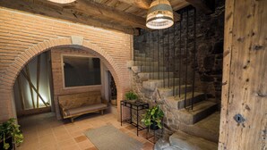 Um interior rústico com uma escadaria de pedra, um banco de madeira e uma lareira.