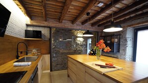 Uma cozinha moderna com bancadas de madeira, micro-ondas embutido e painel de pedra atrás do fogão.