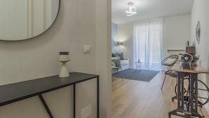 Uma sala de estar moderna com um espelho redondo, uma mesinha com uma vela, um sofá, uma mesa de centro e uma máquina de costura.