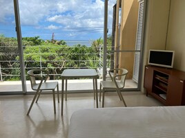 Uma varanda com mesa, cadeiras, uma cama e uma televisão.