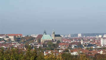 Paisagem urbana com uma igreja em destaque, com telhado verde e duas torres, cercada por edifícios residenciais e árvores.