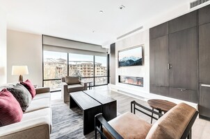 Uma sala de estar moderna com sofá, poltronas, mesa de centro e lareira.