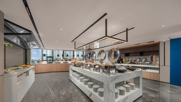 Uma cozinha moderna com bancadas de mármore, uma ilha central com pratos e vista para a cidade.