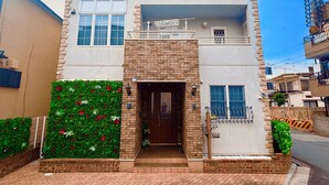 Um edifício de dois andares com fachada de tijolos, varanda e parede verde com flores.
