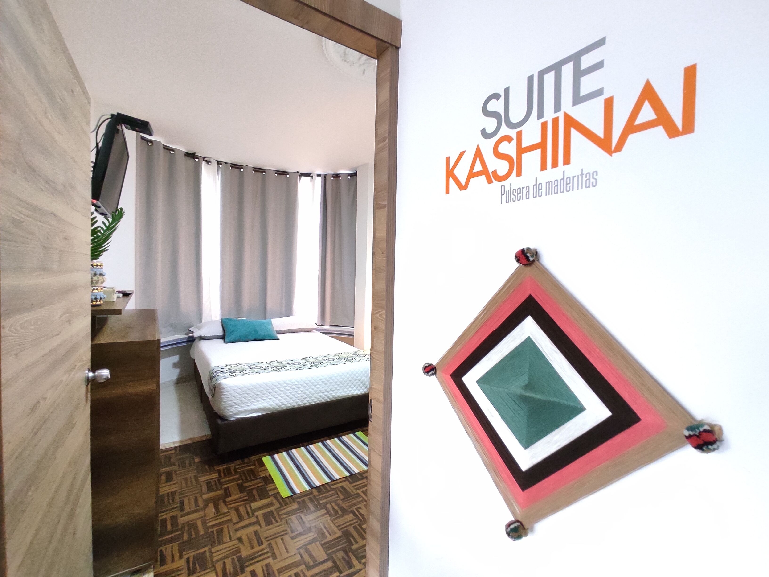 Quarto de hotel com cama, cortinas, piso de madeira e uma parede com pôster.